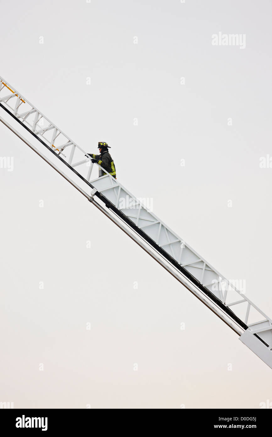 A firefighter climbs a tower ladder during a building fire Stock Photo ...