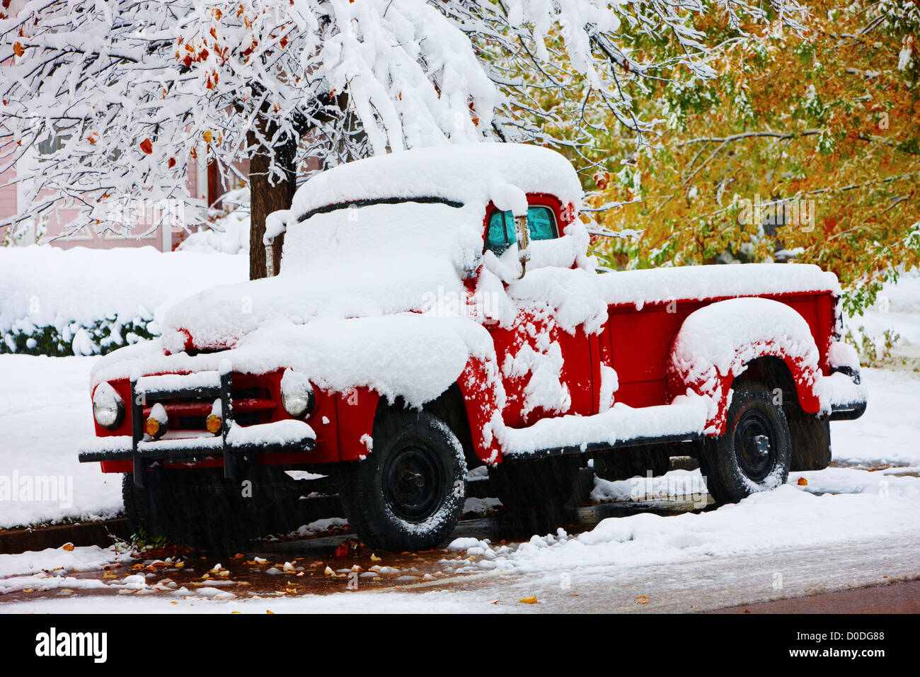 Old red truck, covered in snow, parked on street during a blizzard ...