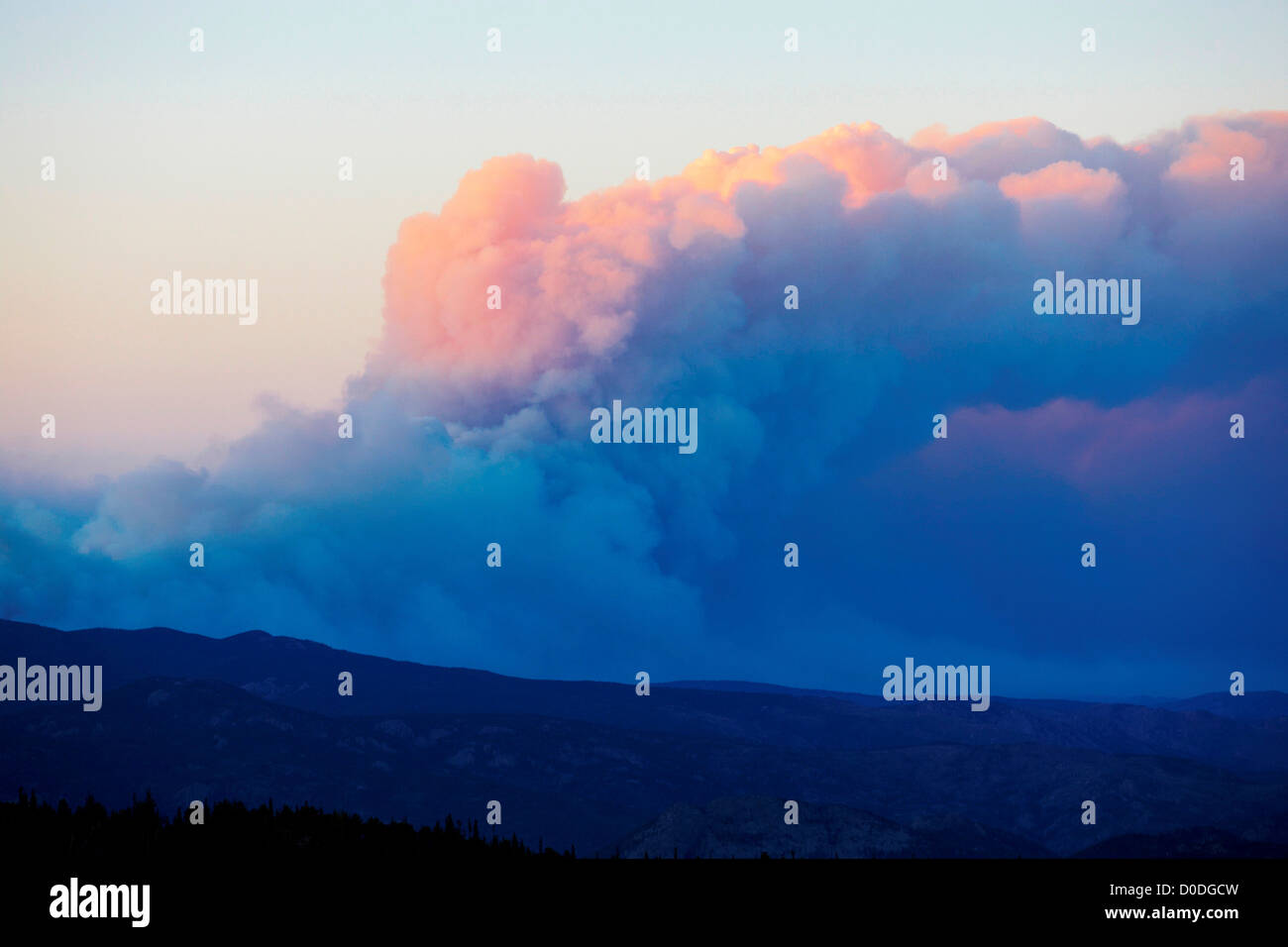 Sunset light on plume of smoke from raging mountain wildfire, as seen ...