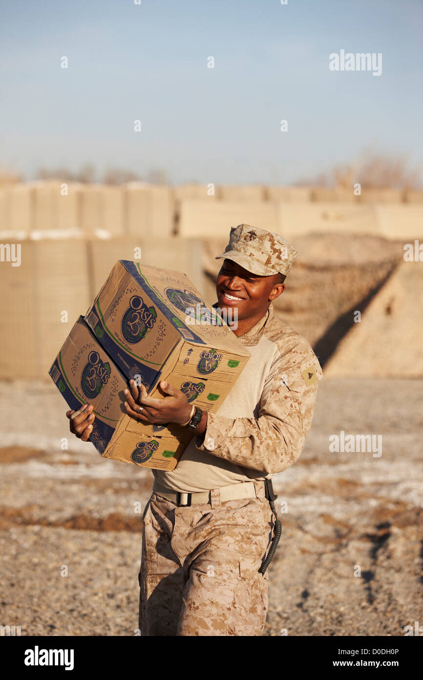 United States Marine carries boxes of bottled water at a forward ...
