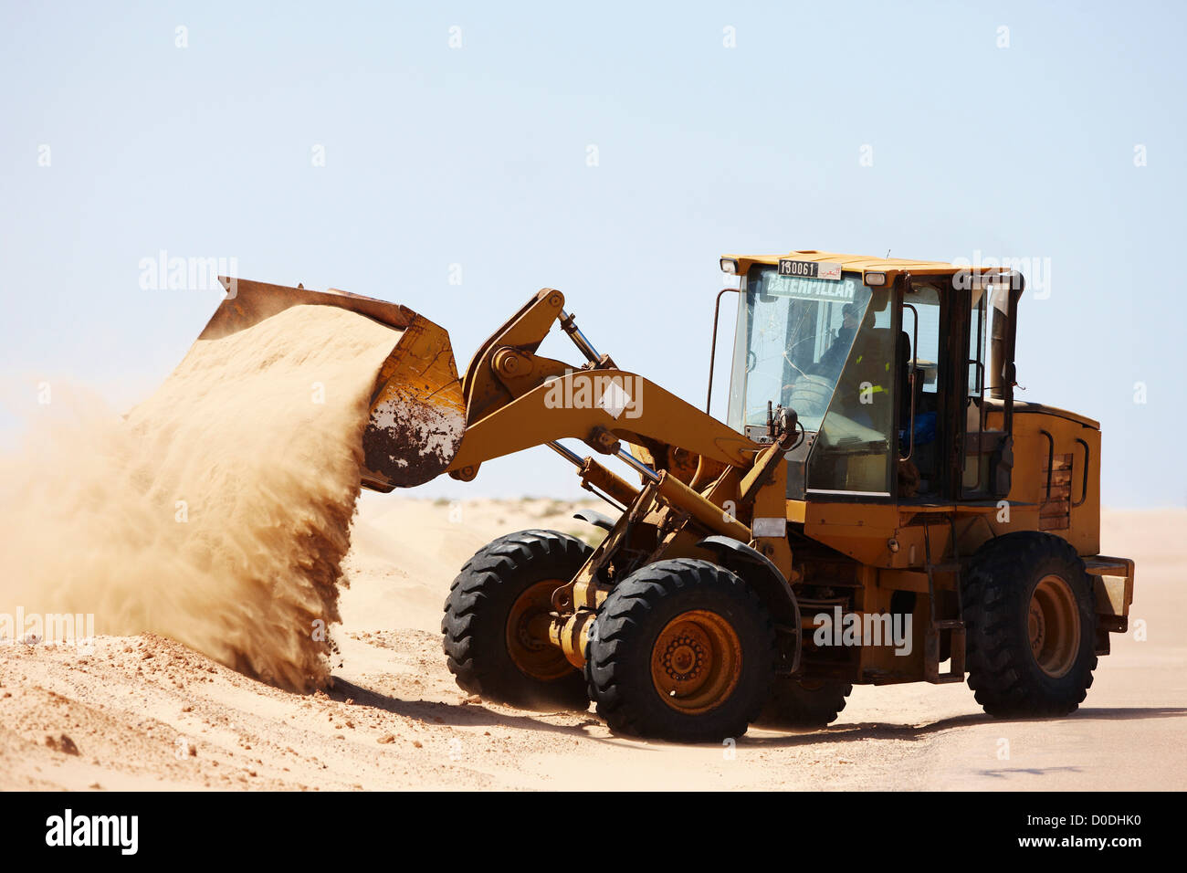 Front end loader removing accumulated sand from roadway, southern ...