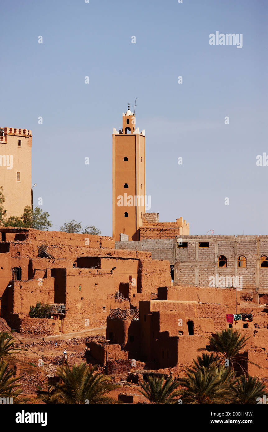 Minaret of a mosque rises above earthen architecture, Morocco Stock ...