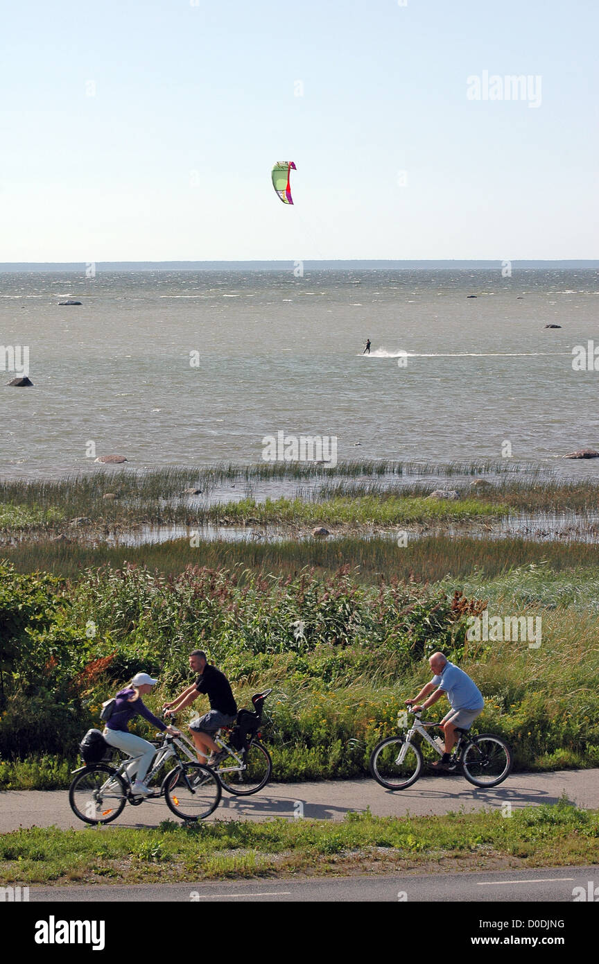 people riding a bicycle with kite-surfers on sea at background Stock ...