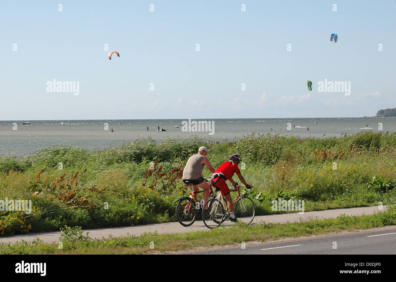 people riding a bicycle with kite-surfers on sea at background Stock ...