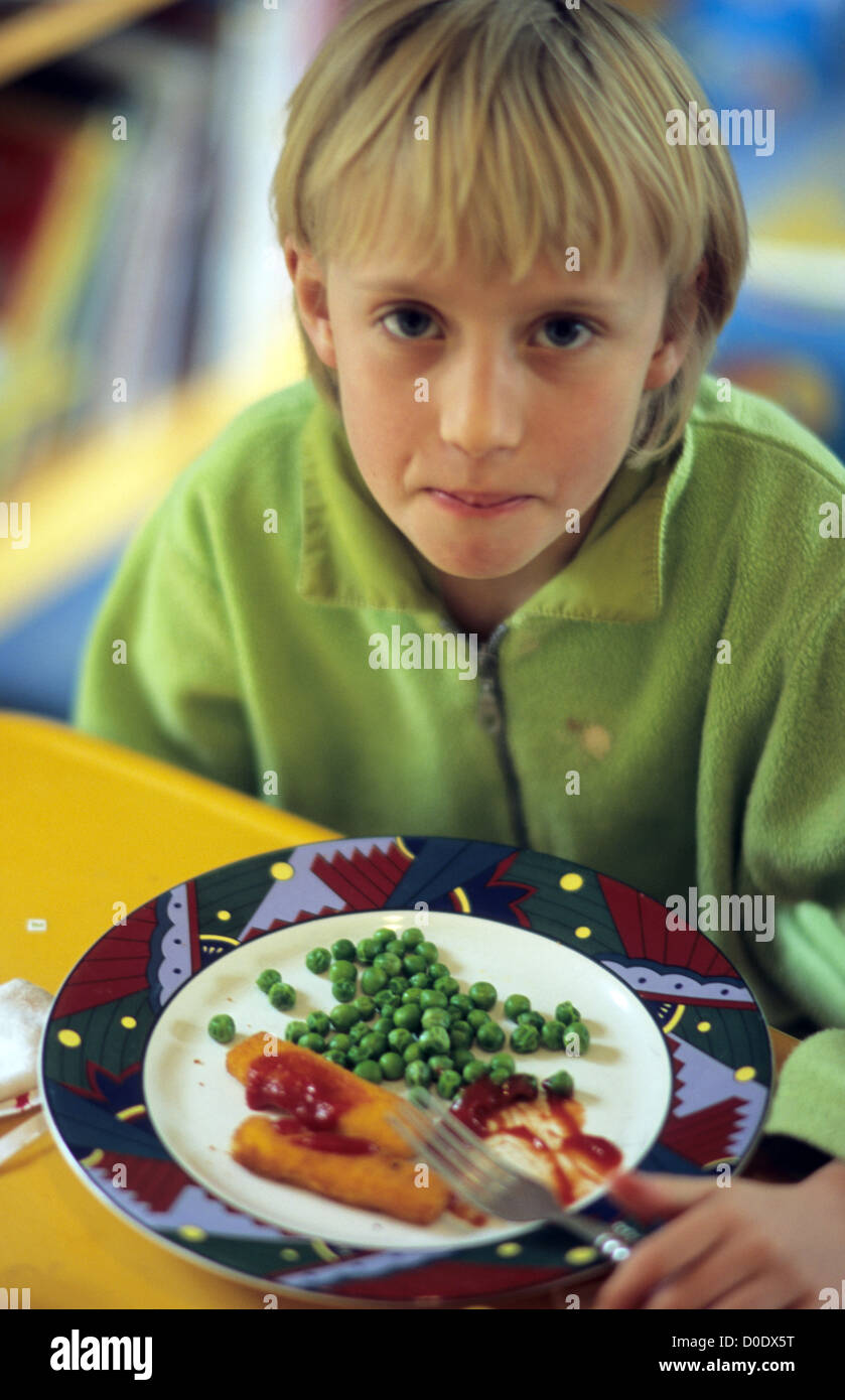 Young girl eating fish fingers and peas Stock Photo - Alamy