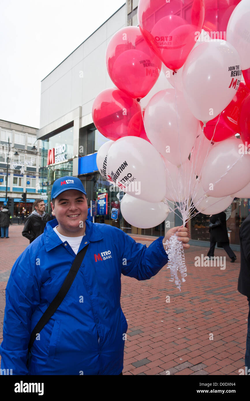 An employee gives away balloons at the opening of the new branch of ...