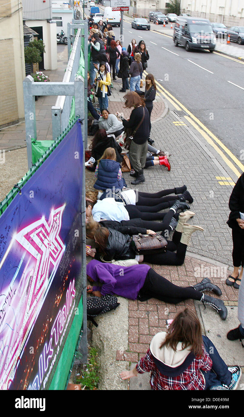 X Factor fans wait to catch a glimpse of the finalists behind a fence ...