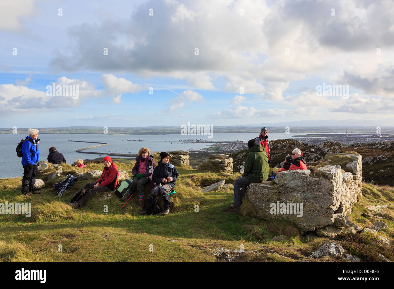 Group of Ramblers resting on old fort ruins on Holyhead Mountain with ...