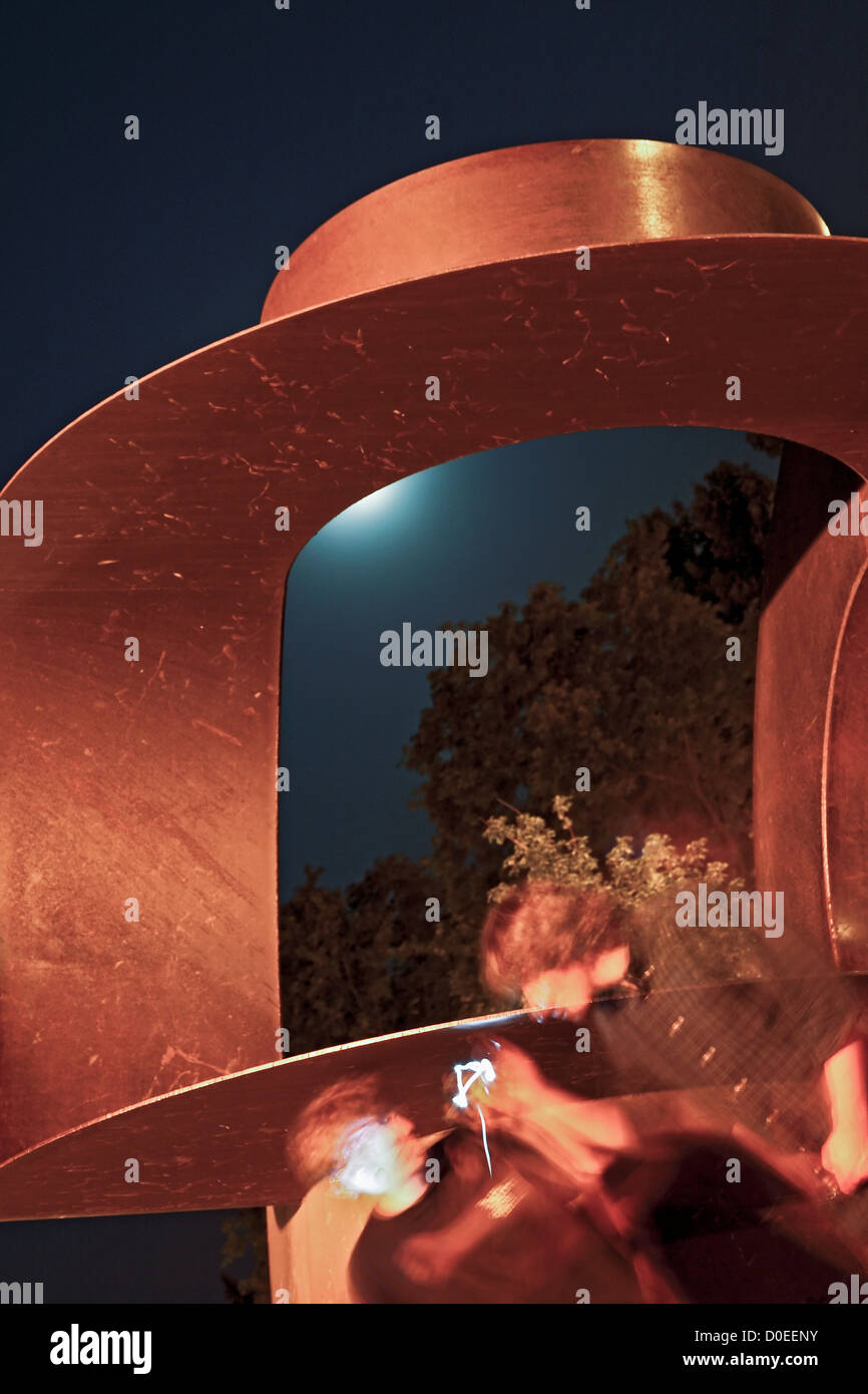 A statue in Denver, Colorado stands backlit by the moon. A figure seems ...