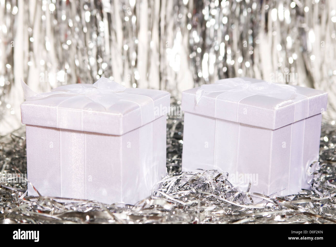Two neatly wrapped gift boxes surrounded by silver foil over white ...