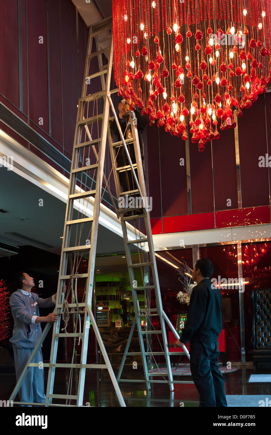 Chinese man up a steep ladder changing a light bulb Stock Photo - Alamy
