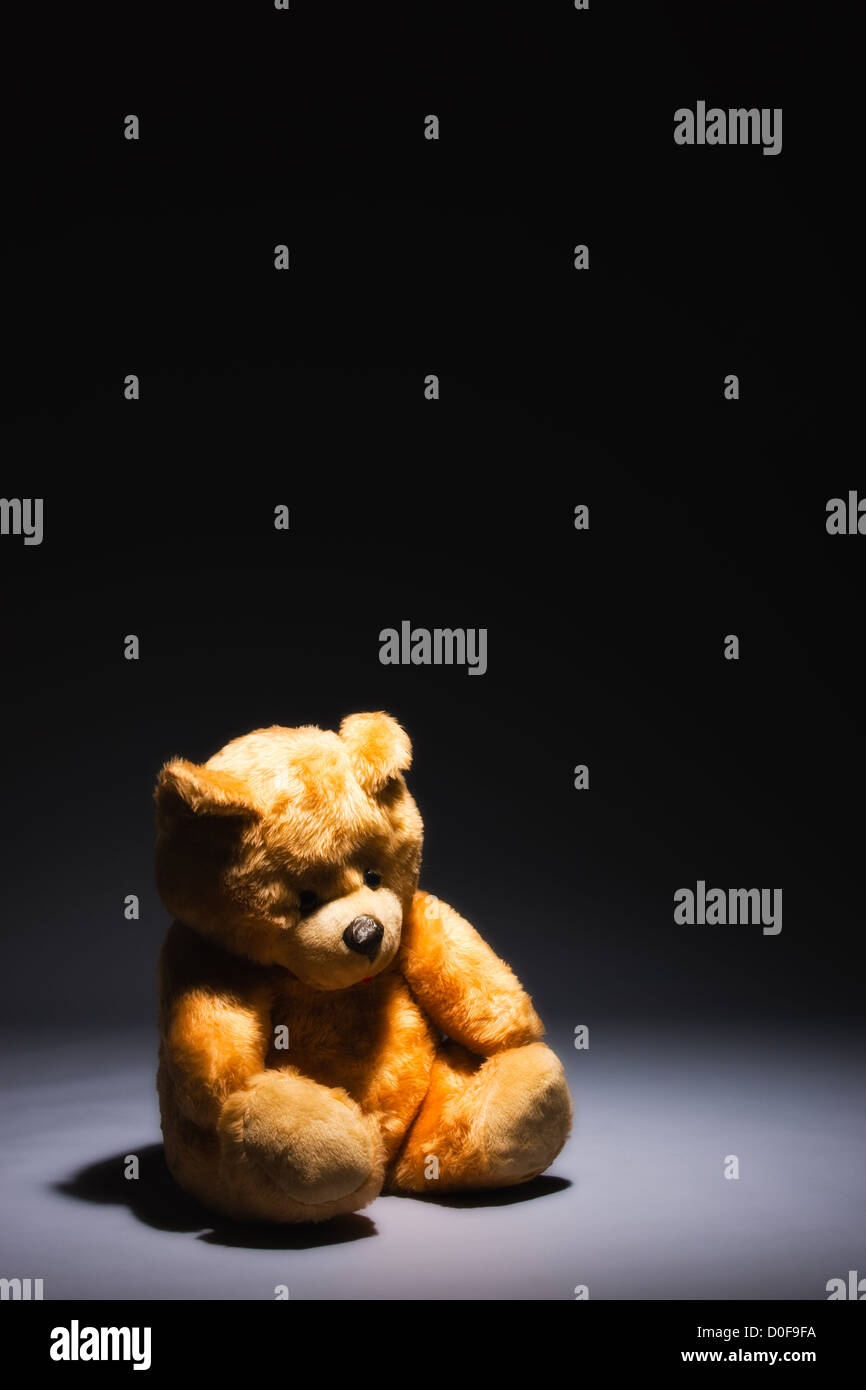 Alone teddy bear sits on a spotlight, vertical format Stock Photo - Alamy