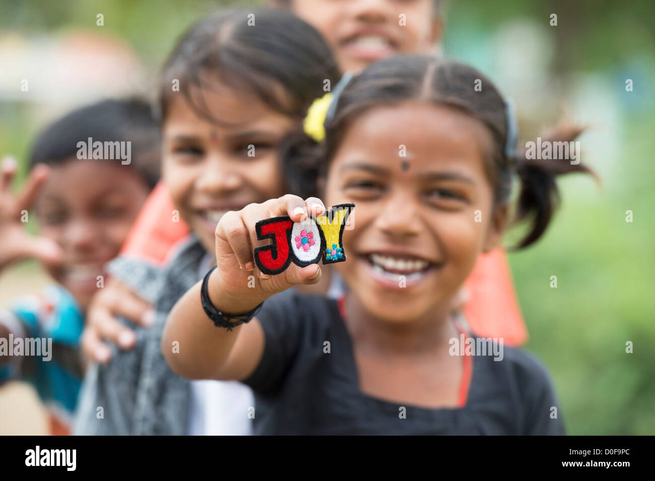 Smiling Indian girl holding a JOY multicoloured embroidery patch. India ...