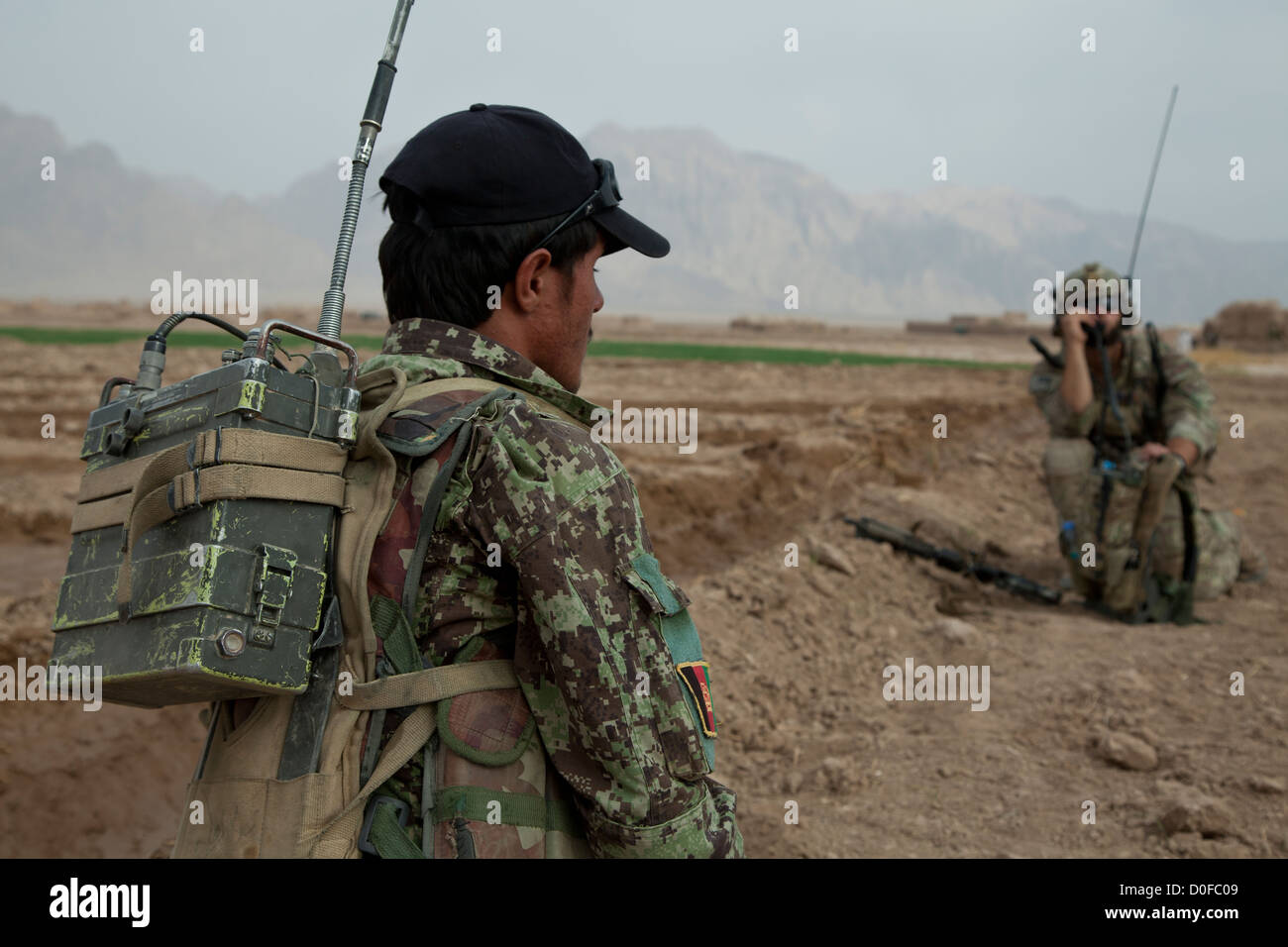 An Afghan National Army soldier watches a US soldier use his radio ...