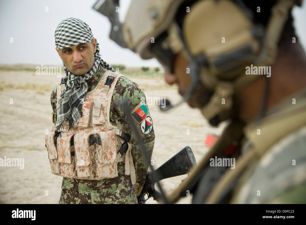 An Afghan National Army commando watches a US soldier use his radio ...