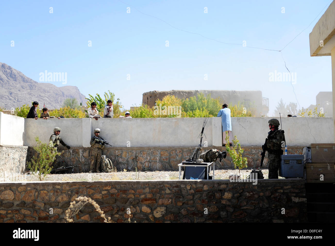 Local children gather as members of the US Army secure a compound ...