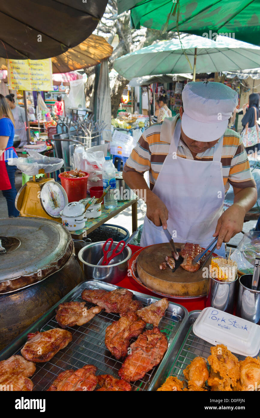 Man slicing and selling cooked pork in a market in Bangkok, Thailand ...
