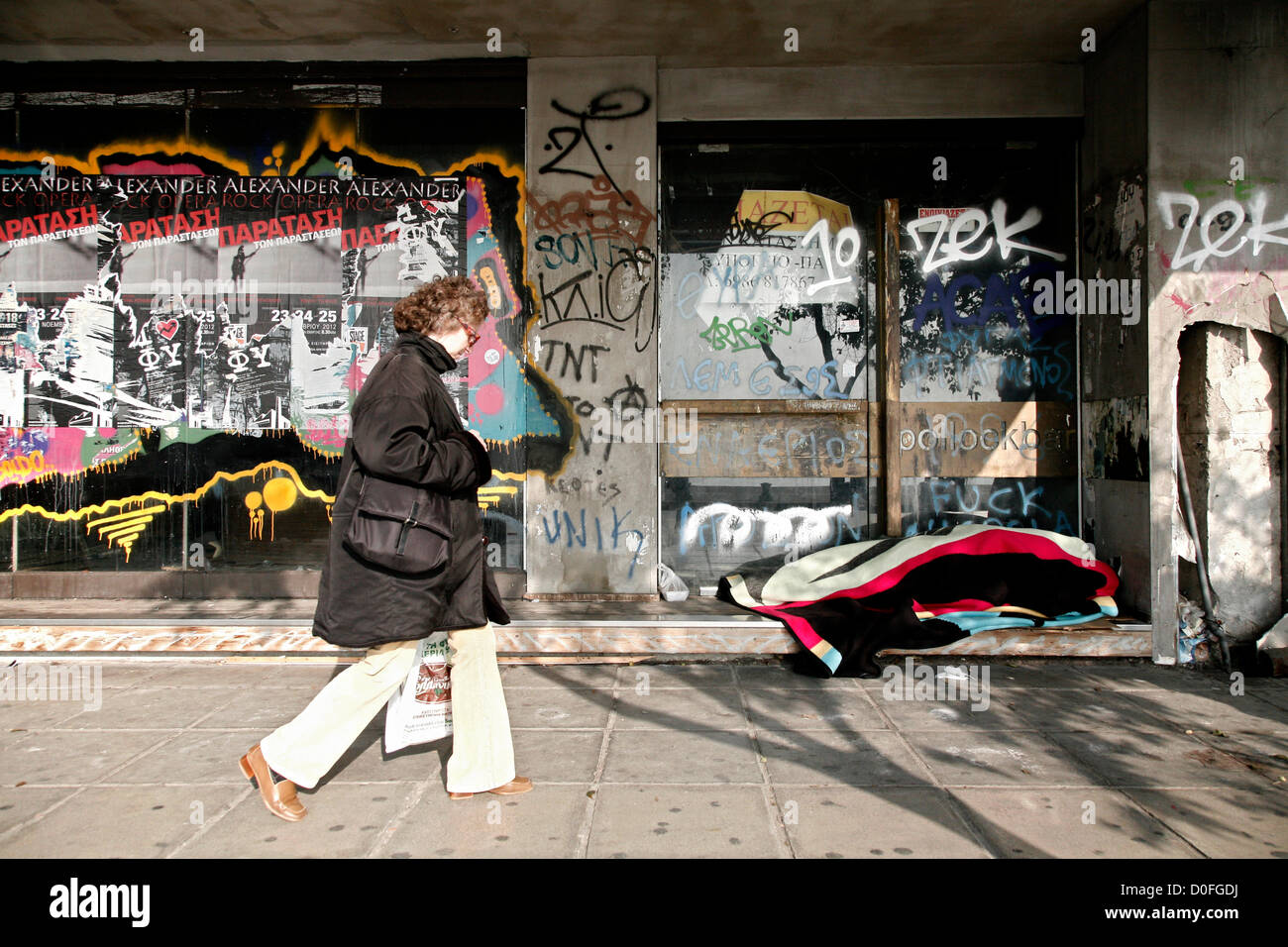 Thessaloniki, Greece. November 24, 2012. A woman walks past a homeless ...