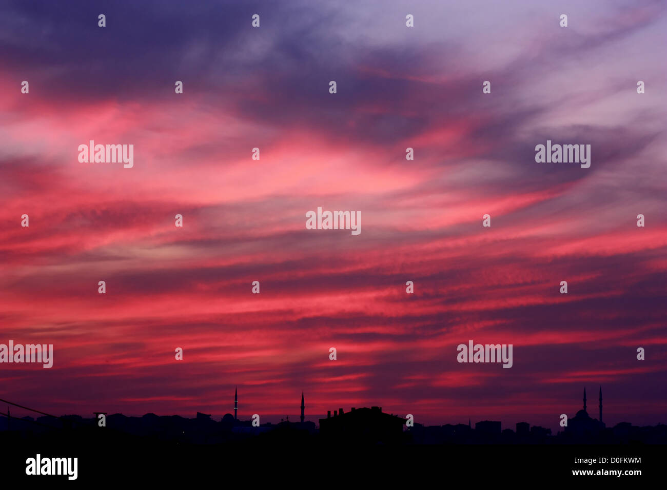 Cloudy red sunset scene with city and mosque silhouette on background ...