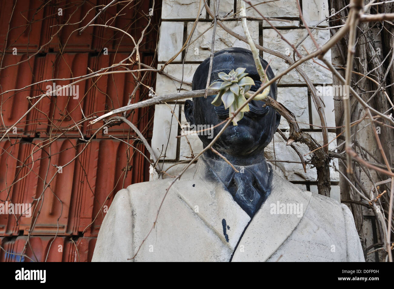Vandalized marble statue obscured by overgrown plants at the abandoned ...
