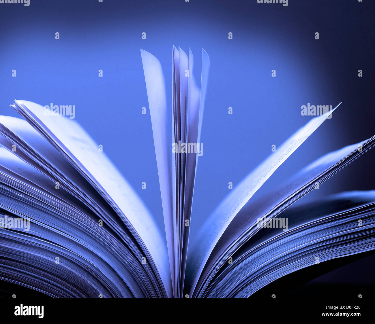 A large single book sitting with pages open on a desk Stock Photo - Alamy