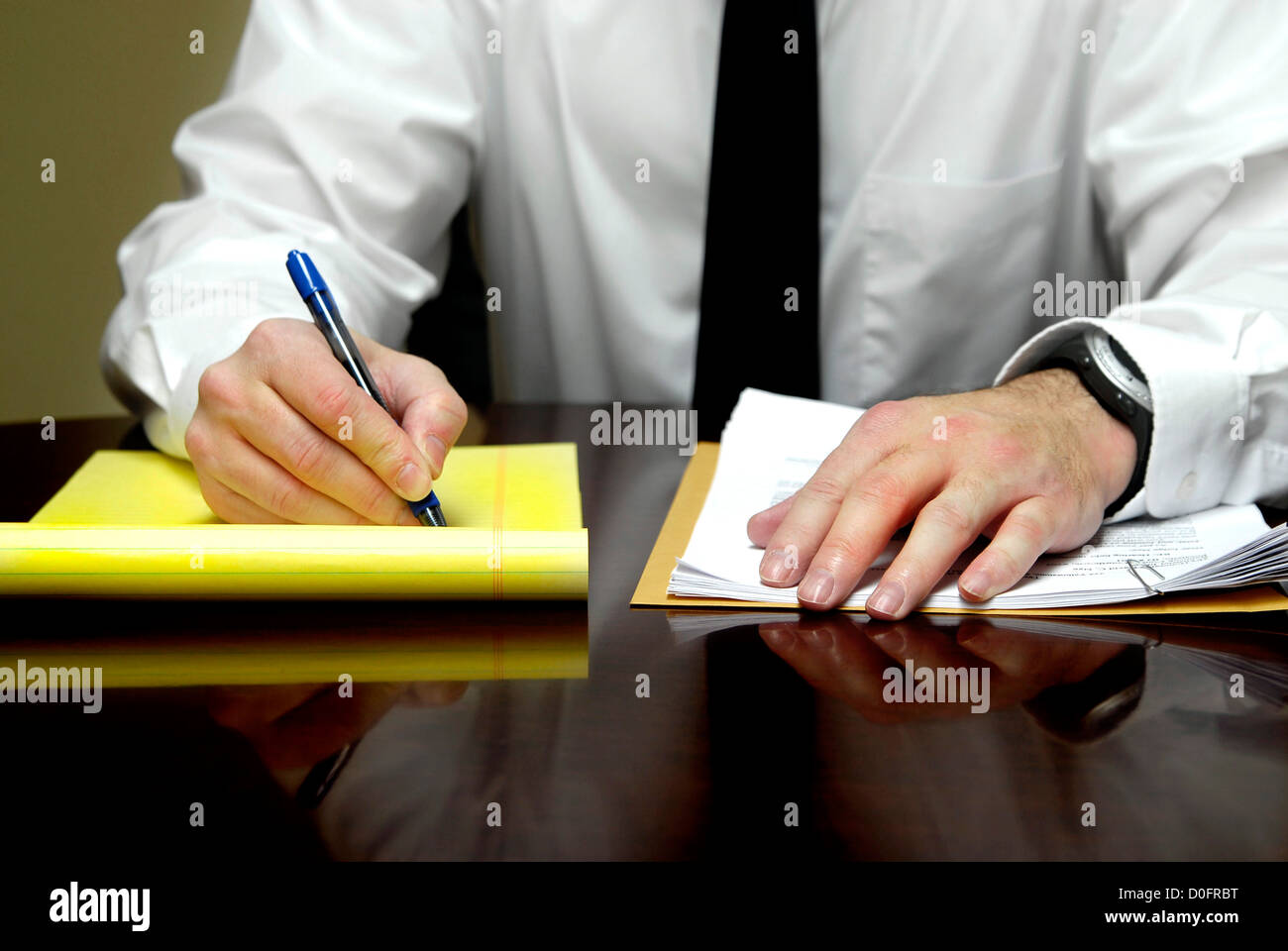 Man sitting at business desk writing on paper with files Stock Photo ...