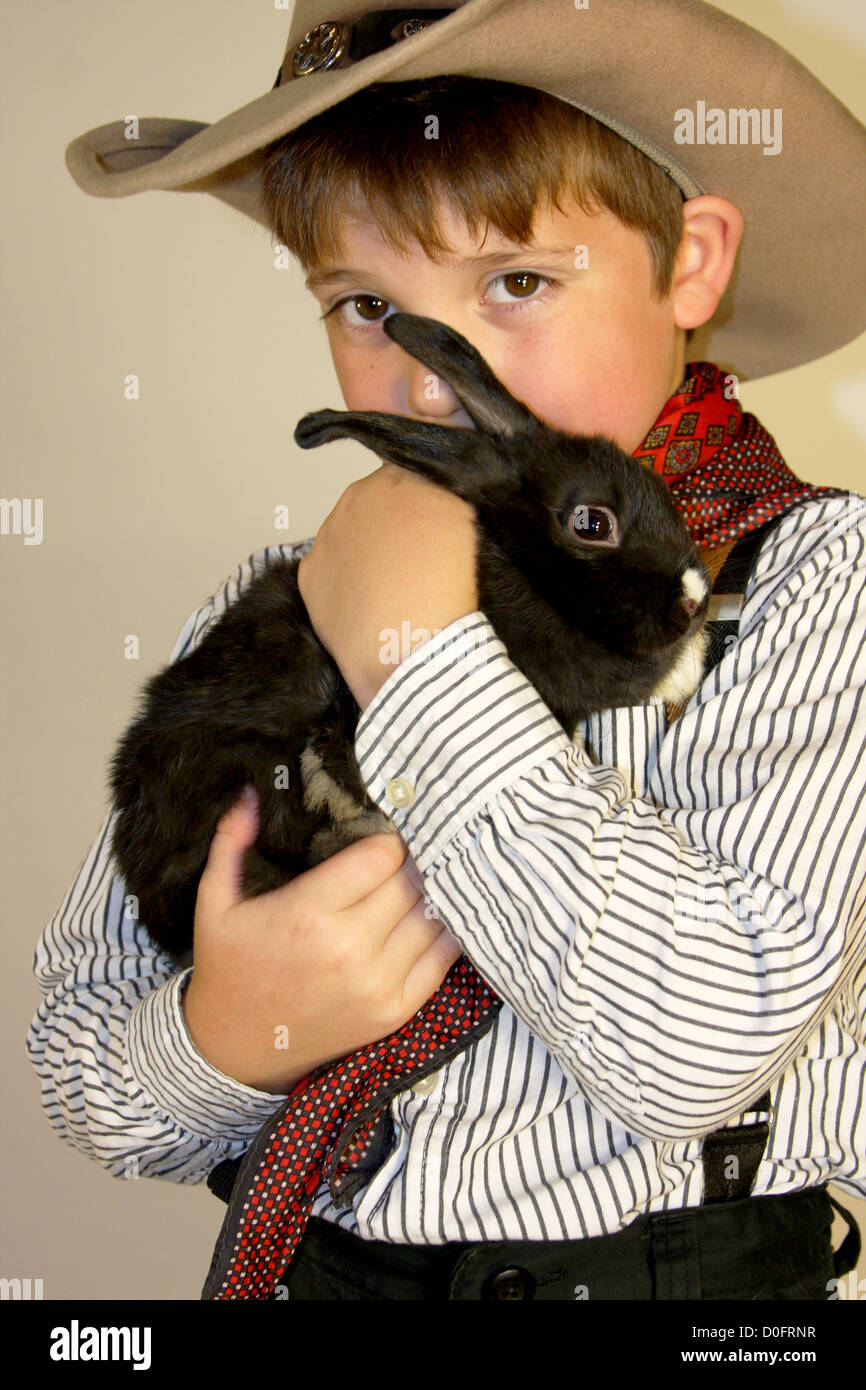 A young cowboy holding a black bunny rabbit tightly Stock Photo - Alamy