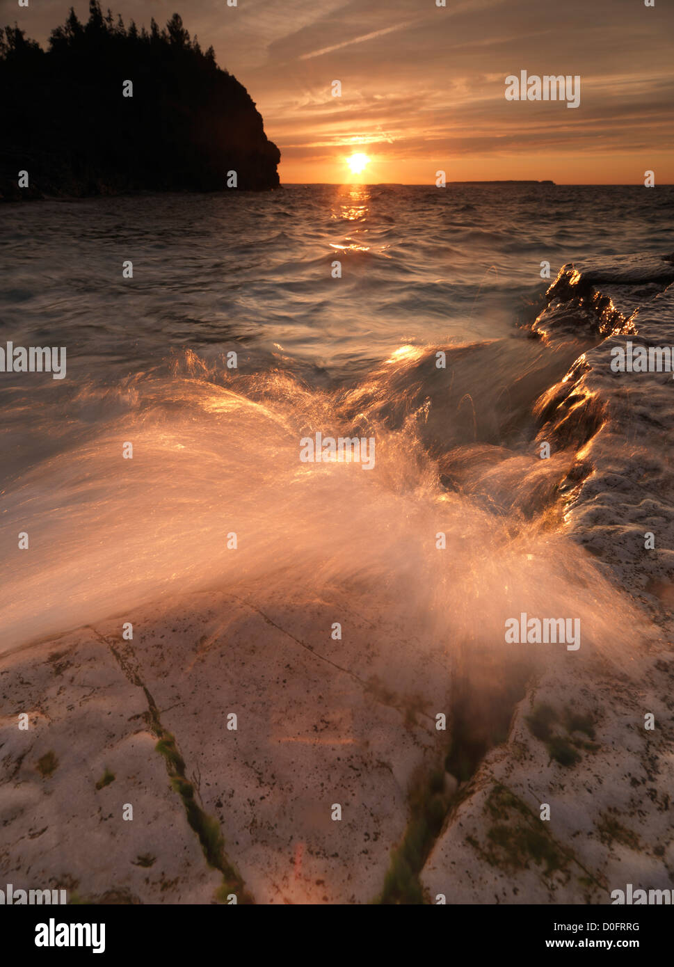 Beautiful sunset nature scenery of waves hitting rocks on a shore of ...