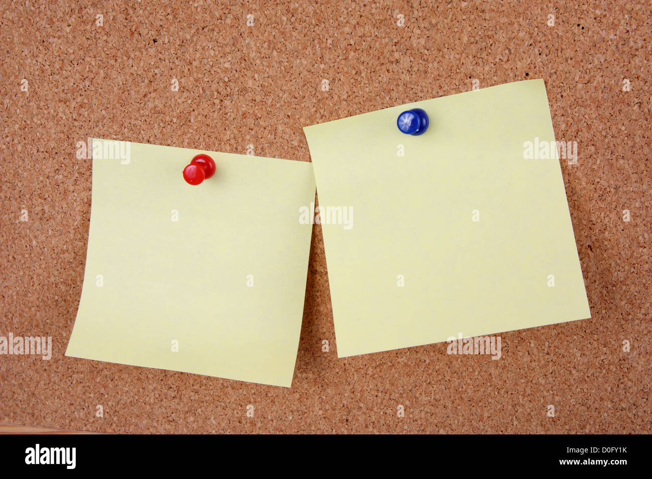 two yellow memo sticks with pins on cork board Stock Photo - Alamy