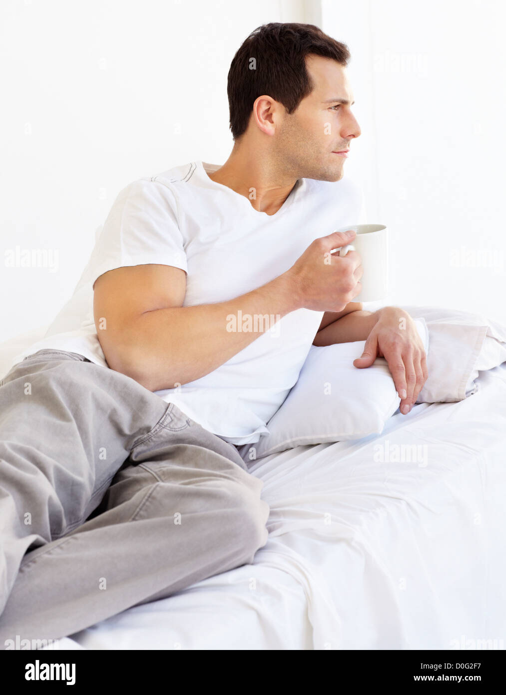 Handsome young man reclining on his bed with a cup of coffee Stock ...