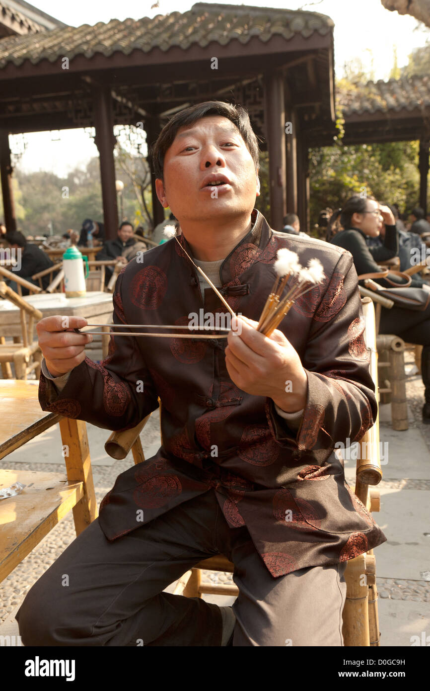 An Ear Cleaner offers his services at Renmen Park Teahouse, in Chengdu ...
