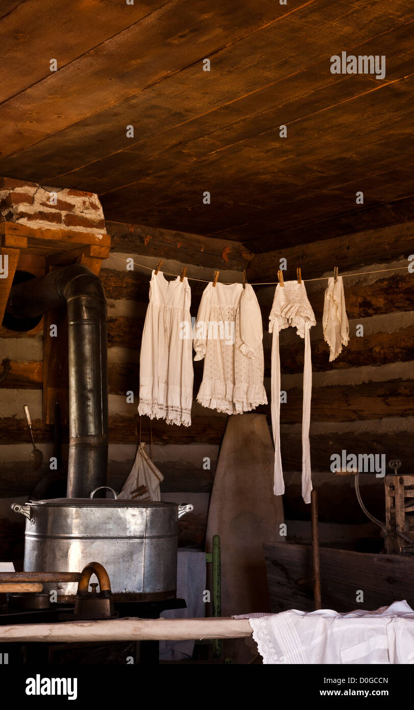 Historic interior old cabin kitchen, antique baby clothing hanging on a ...