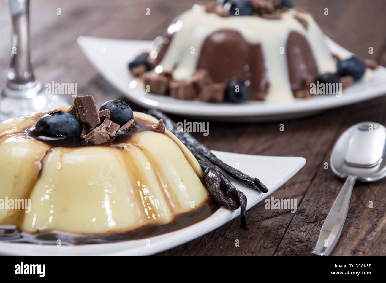 Different sorts of Pudding topped with sauces on wooden background ...