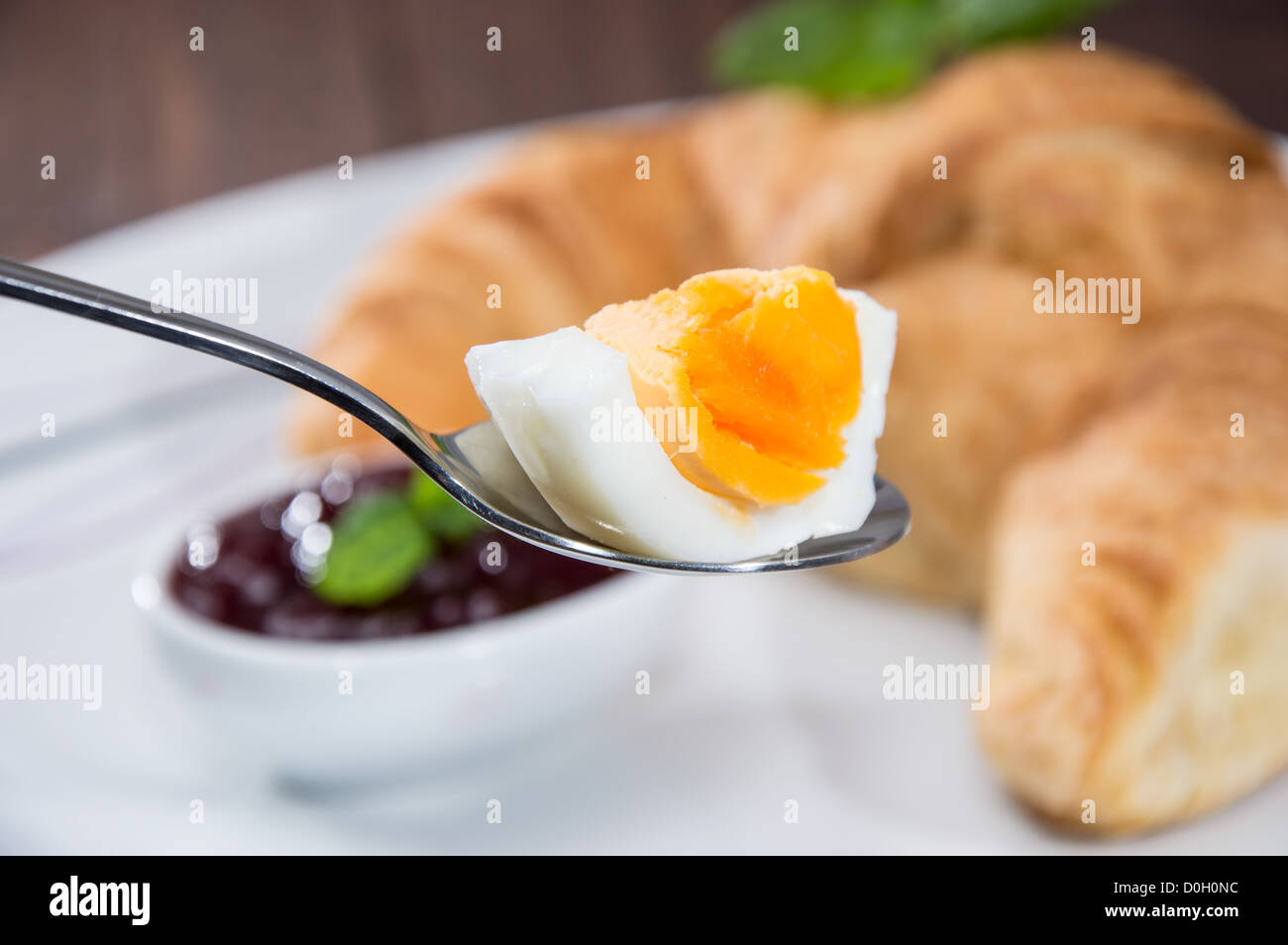 Spoon with piece of egg and croissant in the background Stock Photo - Alamy