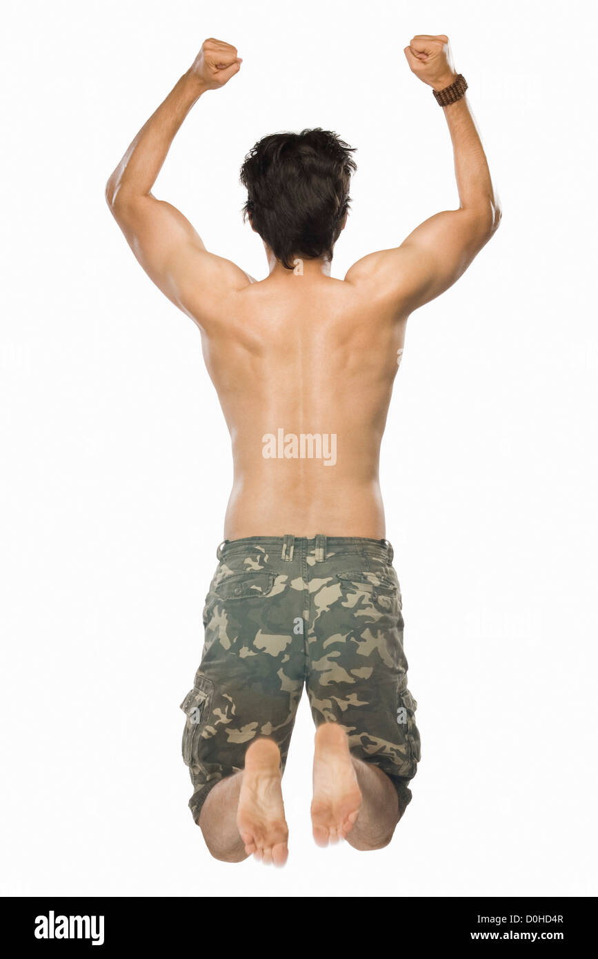 Rear view of a young man jumping with joy Stock Photo - Alamy