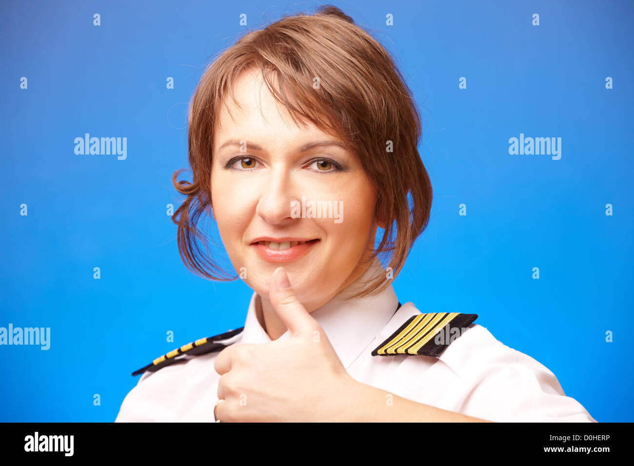 Beautiful airline pilot wearing uniform with epauletes showing thumb up ...