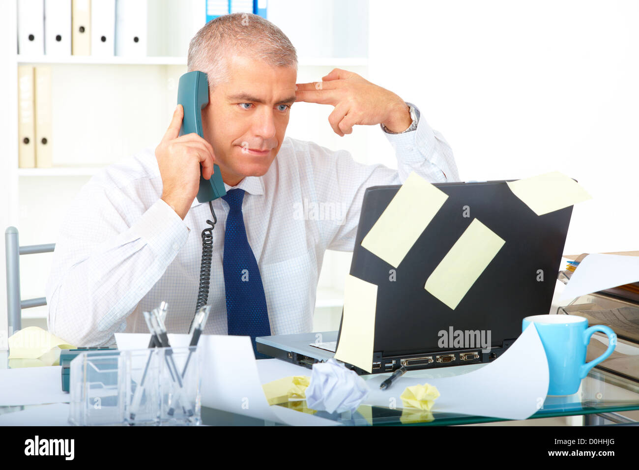 Stressed overworked mature businessman sitting at desk with phone and ...