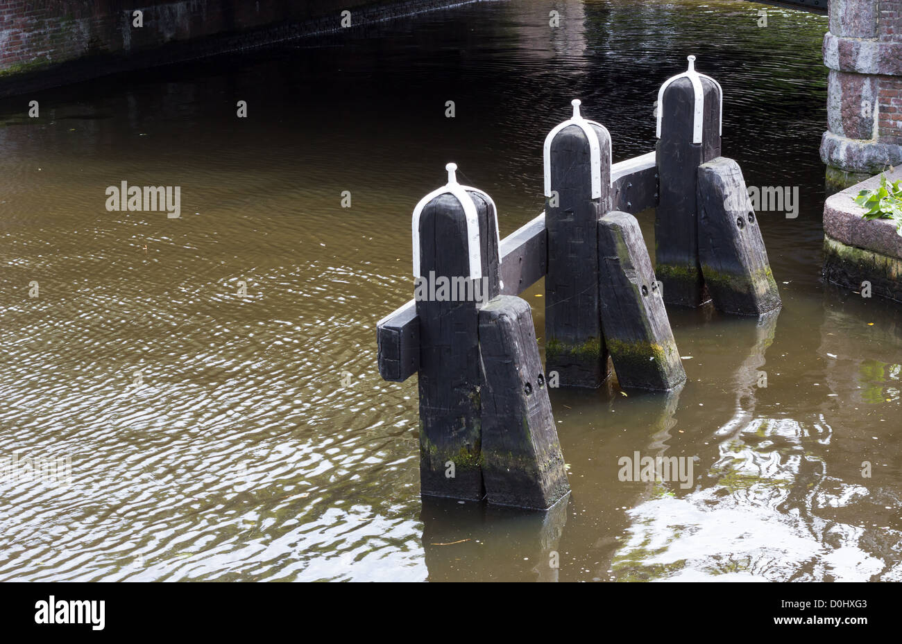 Bollards in a canal, in front of a bridge, of a Dutch city Stock Photo ...