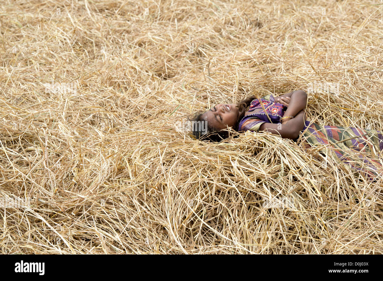 Young Smiling happy Indian girl laying in straw. Andhra Pradesh. India ...