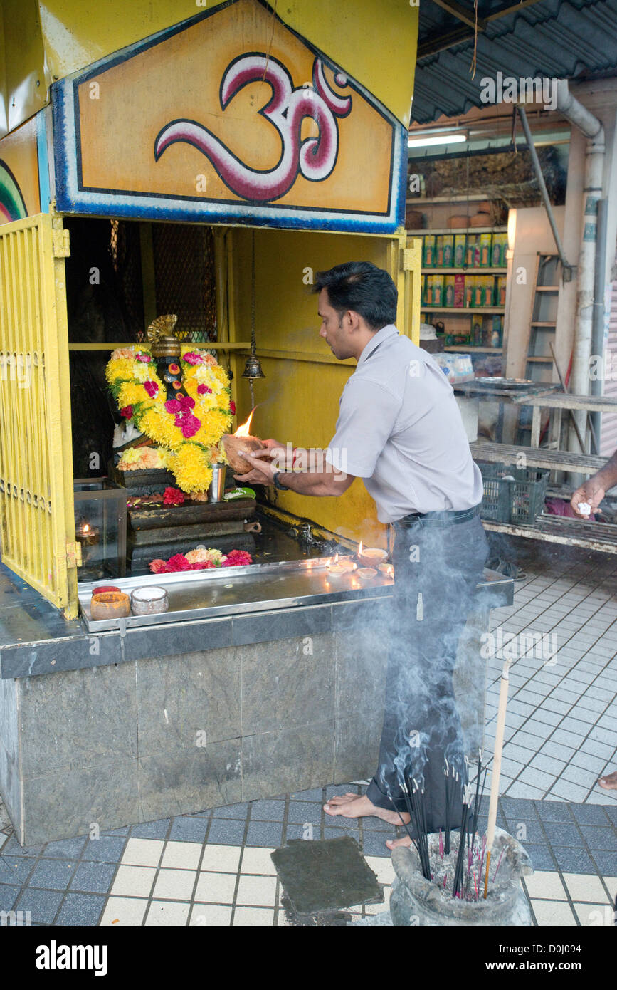A Hindu devotee makes offerings at a Ganesh Shrine in Little India ...