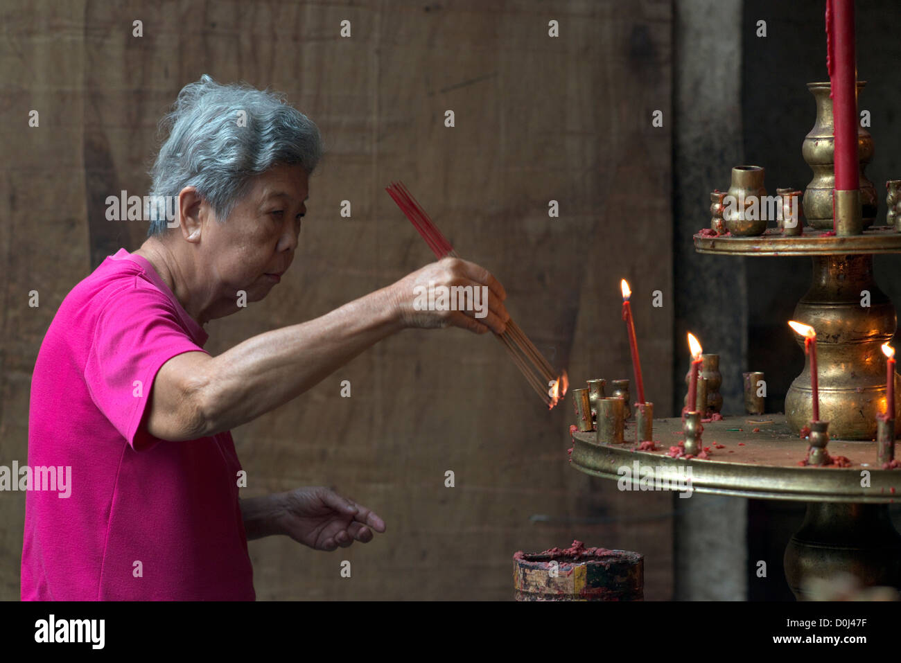 A Tao Buddhist devotee lights incense sticks at the Goddess of Mercy ...