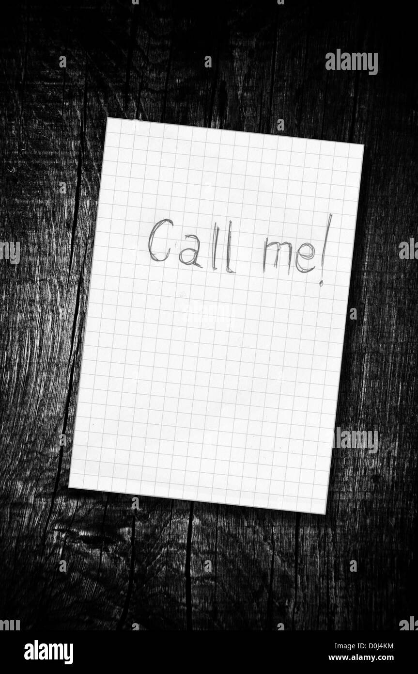 Call me, reminder paper note over a wooden background, black and white ...