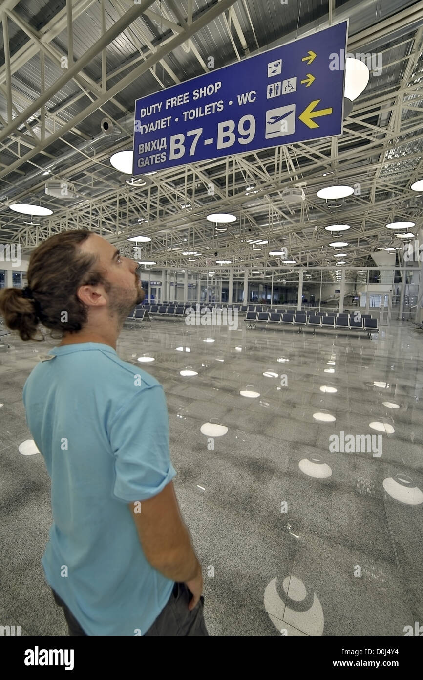 Young man looking direction billboard in airport Stock Photo - Alamy