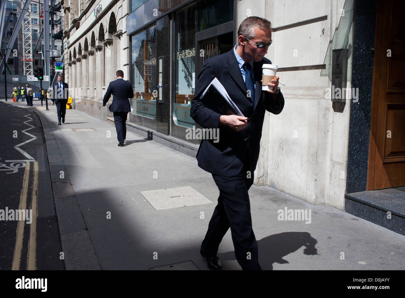 A businessman walking down a street drinking coffee Stock Photo - Alamy