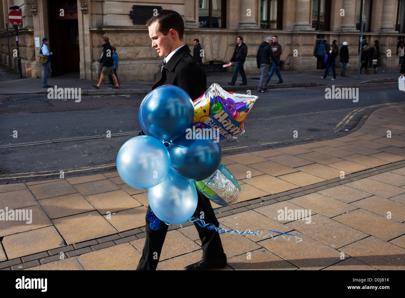 A man walking with some balloons in Cheltenham Stock Photo - Alamy