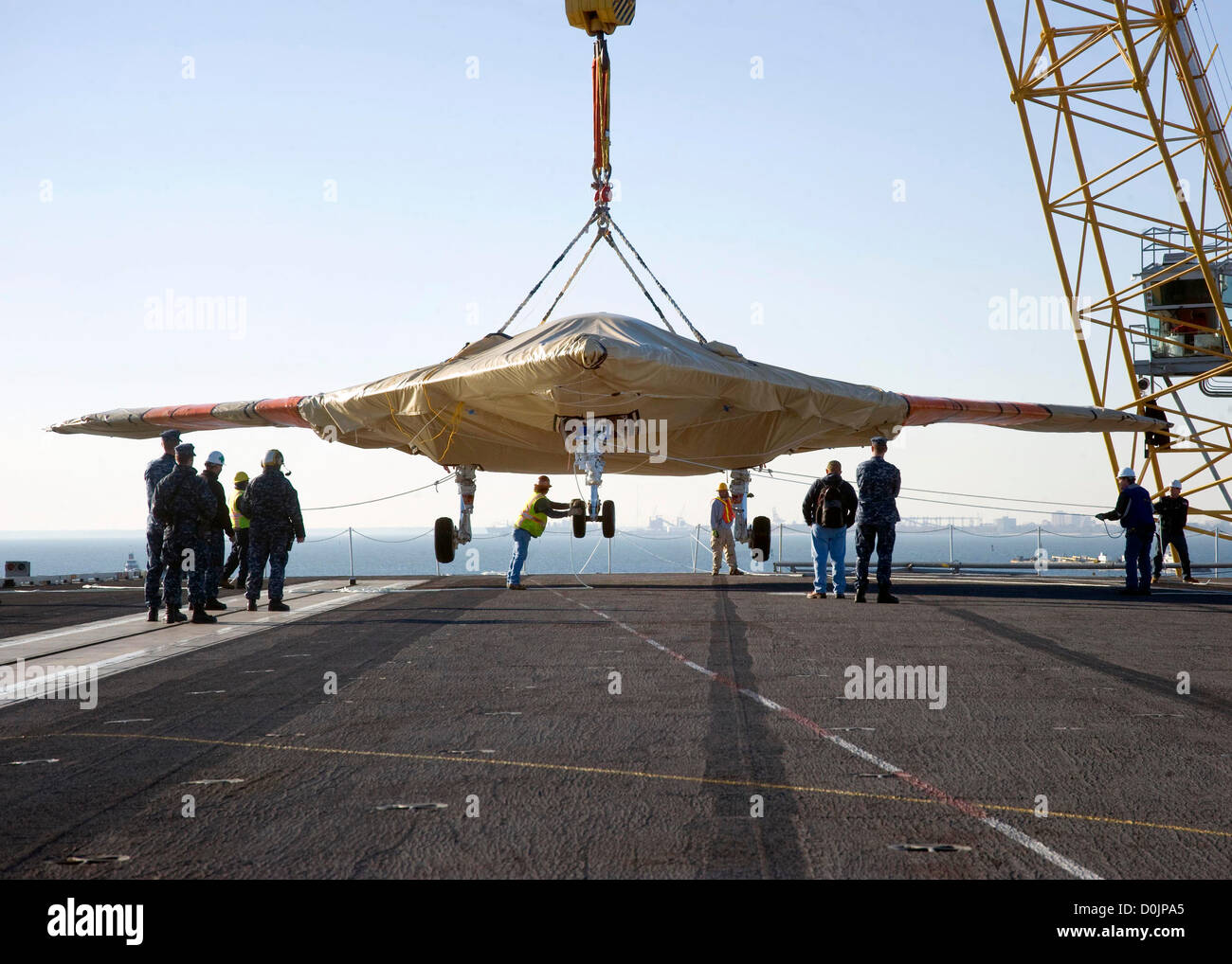 An X-47B Unmanned Combat Aircraft is transferred to the flight deck of ...