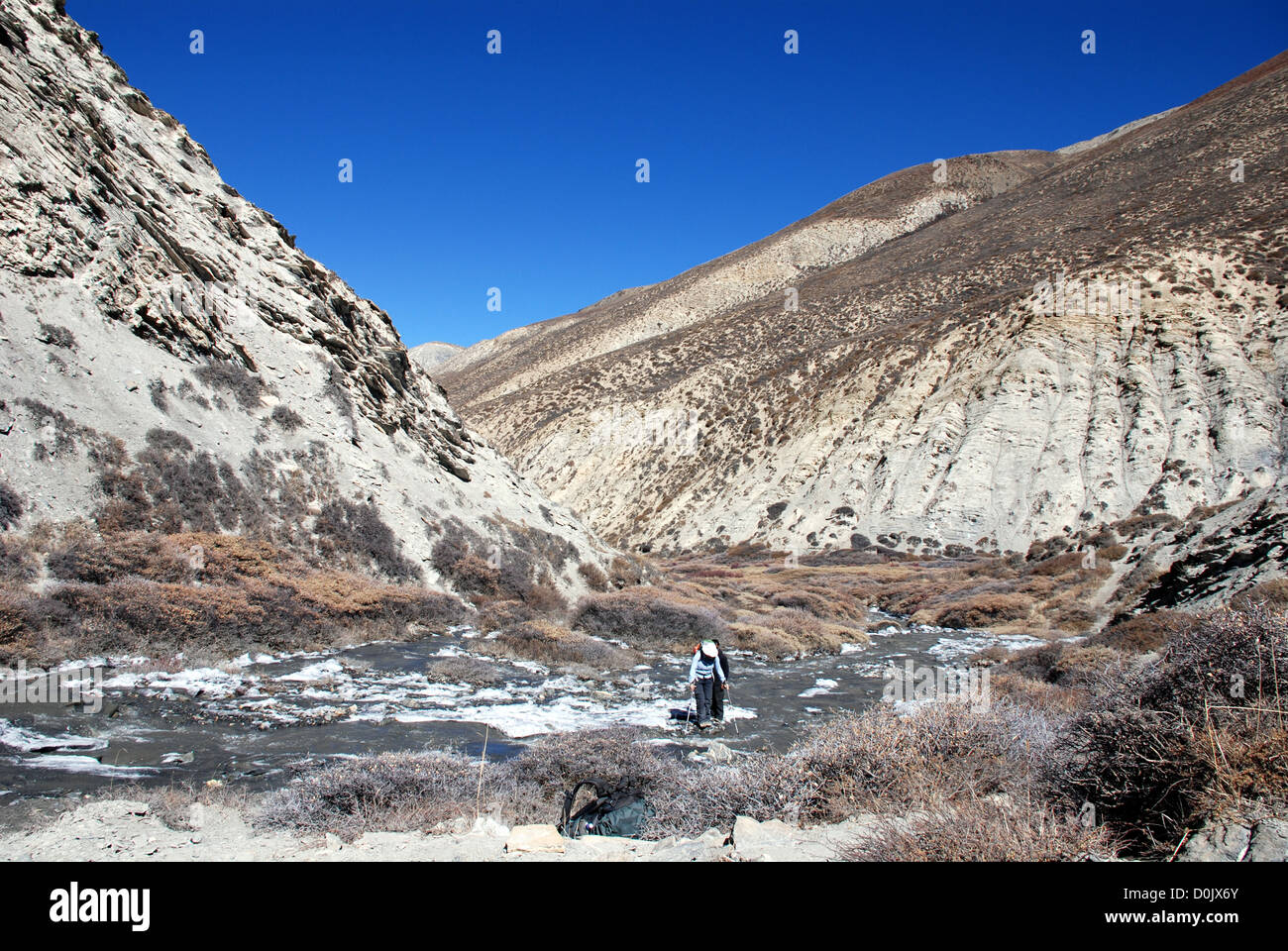 a trekker crossing a small river close to the village of Sibu in the ...