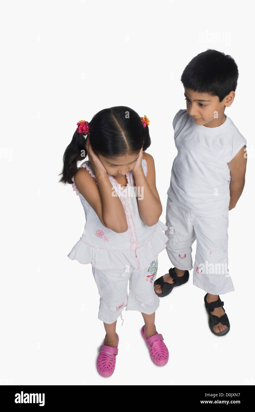 Girl covering her ears while her brother talking Stock Photo - Alamy