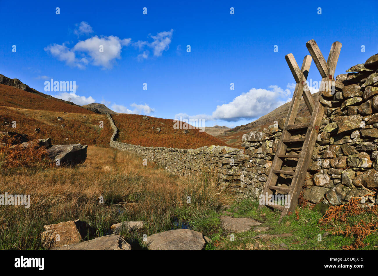 A stone wall leads from a wooden stile to the hills beyond Stock Photo ...