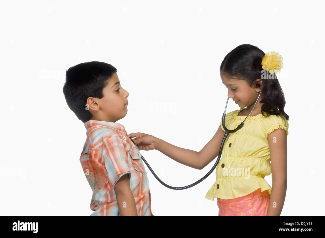 Side profile of a girl examining a boy with a stethoscope Stock Photo ...